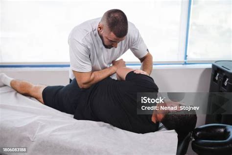 Young Chiropractor Massaging His Client On The Massage Table Stock