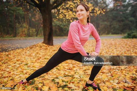 친절 하 고 쾌활 한 젊은 여자 공원에서 밖에 서 스트레칭 그녀는 측면을 보인다 여자는 한쪽 무릎에 손을 잡으십시오 그녀는 혼자 긍정적 이다 사람들에 대한 스톡 사진 및