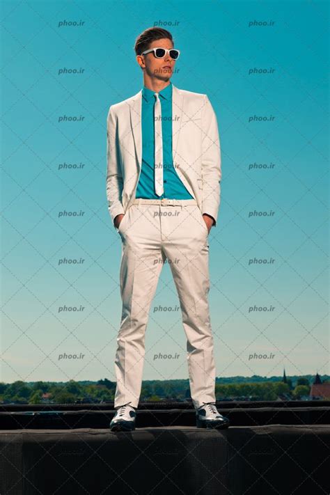 عکس با کیفیت مرد با پیراهن آبی و کت و شلوار سفید و پس زمینه آسمان آبی زیبا عکس با کیفیت و