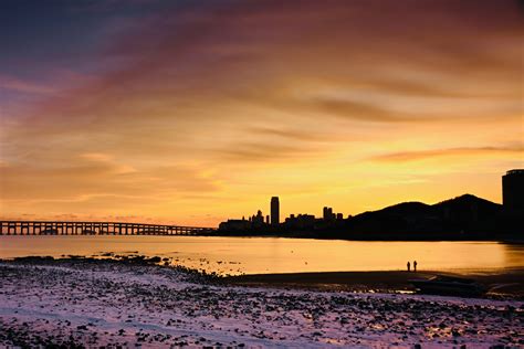 배경에 다리가 있는 해변의 일몰 전망 사진 Unsplash의 무료 바닷가 이미지