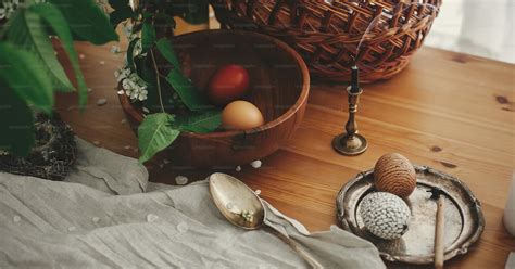 현대적인 왁스 장식품과 천연 염색 달걀이 있는 세련된 부활절 달걀은 봄 꽃 바구니 양초 린넨 천 Buxus가 있는 소박한 나무 테이블에 있습니다 행복한 부활절