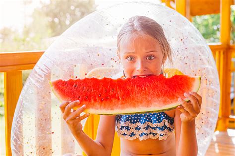 여름 테라스에있는 소녀는 붉은 수박과 미소의 큰 조각을 먹는다 음식 자연 여름에 잘 익은 육즙이 많은 수박을 먹는 소녀 사랑스러운 금발 소녀는 야외에서 수박 조각을 먹습니다