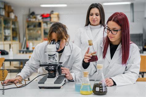 Adult Woman Examining Sample In Microscope Near Babe Women With Chemical Liquids During