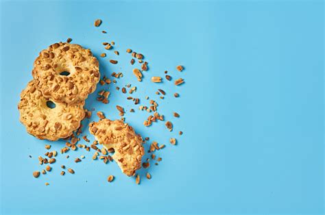 땅콩과 부스러기가있는 신선한 원 귀리 쿠키의 전체 및 반쪽은 부엌의 파란색 책상에 놓여 있습니다 텍스트의 공백입니다 맨 위 보기 건강한 식생활에 대한 스톡 사진 및 기타