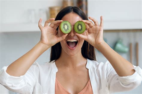 집에 있는 부엌에서 키위 조각을 들고 포즈를 취하는 재미있는 젊은 여자 젊은 여자에 대한 스톡 사진 및 기타 이미지 젊은 여자 키위 1개월 Istock