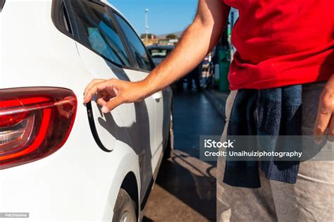 흰색 자동차에서 휘발유나 디젤 연료에 연료를 보급하기 위해 자동차 노즐을 여는 남자 교통 에너지 위기 석유 위기의 개념 가스 펌프의 가격 위기 속에서 가득 찬 탱크 가격에
