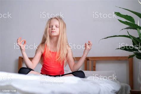 어린 금발 소녀는 명상과 요가 집에서 운동 침대에 연꽃 위치에 앉아에 종사한다 휴식 가정 생활에 대한 스톡 사진 및 기타 이미지 가정 생활 가족 건강한 생활방식