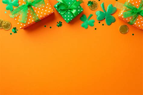 성 패트릭의 날 개념 활 금화 토끼풀과 클로버 모양의 색종이 조각이 있는 선물 상자의 상위 뷰 사진 복사 공간이 있는 격리된 주황색 배경 3월에 대한 스톡 사진 및 기타