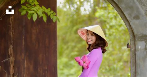 갈색 나무 벽 옆에 서 있는 갈색 모자를 쓰고 보라색 긴 소매 드레스를 입은 여자 사진 Unsplash의 무료 베트남 이미지