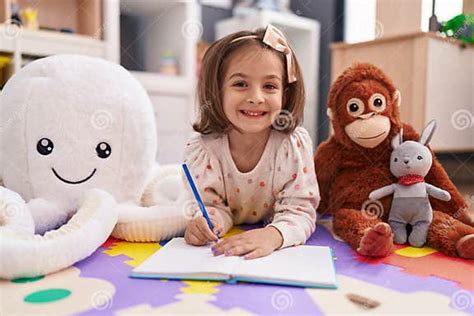 Adorable Hispanic Girl Drawing On Notebook Lying On Floor At