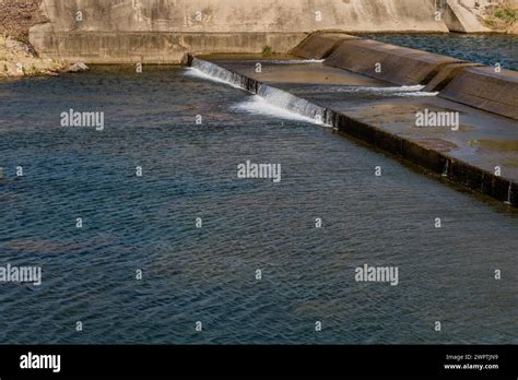 Bright Daylight Captures Water Flowing Smoothly Over A Concrete Overflow Structure In South