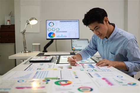 데스크톱 모니터에서 마케팅 보고서를 분석하고 종이 그래프 재무 통계 및 스타트업 프로젝트 인포그래픽을 검토하는 데 집중하는 사업가 개념에 대한 스톡 사진 및 기타 이미지