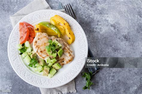 토마토와 고추 그릴와 아보카도를 회색 돌 테이블 배경에 접시에 오이 살사 닭 가슴살 구이 건강 한 클린 다이어트 저녁 식사 개념입니다 상위 뷰 복사 공간 가금류에 대한 스톡