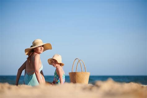 Premium Photo Mother And Daughter Sunbathing On Beach