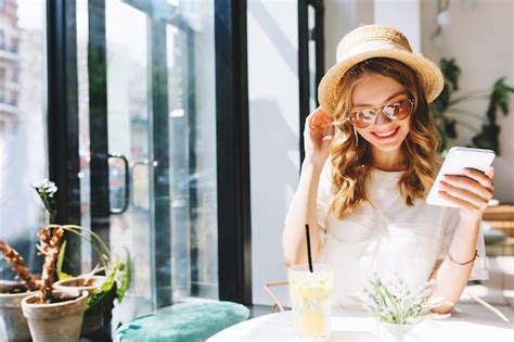 Free Photo Smiling Cute Girl In Straw Hat Relaxing In Cafe Beside Glass Door Holding