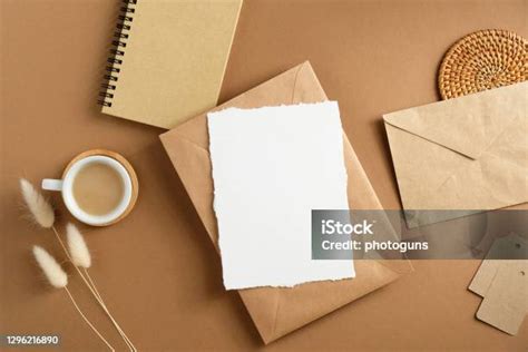 빈 종이 카드와 봉투 모형은 커피 메모장 말린 꽃 한 잔과 함께 갈색 테이블에 모형 플랫 레이 맨 위 보기입니다 가을에 대한