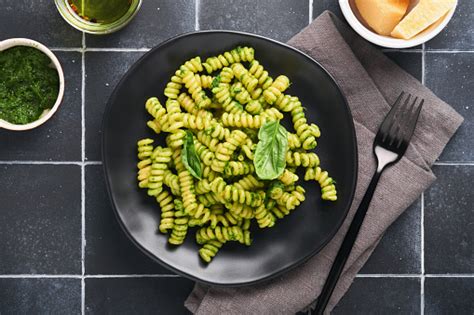 페스토와 이탈리아 푸실리 파스타 검은 돌 조리대 배경에 검은 접시에 바질 페스토와 허브 파르 메산 치즈 바질 및 마늘을 곁들인 Fusilli 파스타 상단 보기 공간을