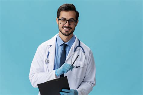 흰 코트와 안경을 쓴 남자 의사 의료 기록과 청진기가 있는 파란색 고립된 배경 복사 공간 텍스트 공간에 미소를 짓고 있습니다