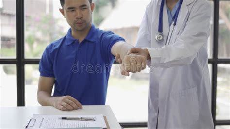Female Doctor Giving Male Patient Physiotherapy With Hand Lift Asian