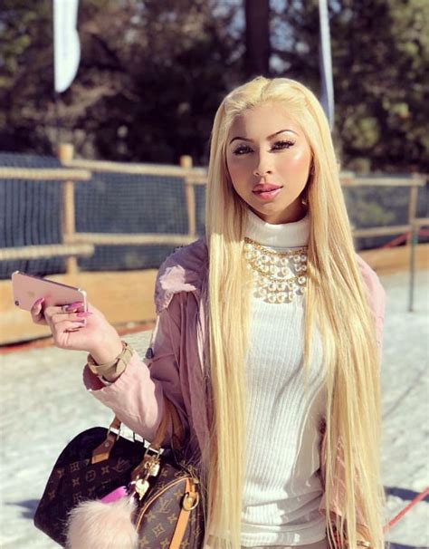 A Woman With Long Blonde Hair Holding A Cell Phone In Her Hand And