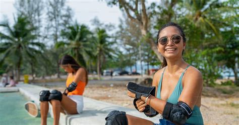 스케이트보드 공원에서 스케이트를 타기 위해 안전 스케이트보드 장갑을 끼고 여자 친구와 함께 있는 아시아 여성 행복 한 여성 우정 여름 야외 활동적인 라이프 스타일 놀이