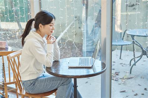 아시아 한국의 카페 테이블에 앉아서 노트북을 바라보며 강의를 듣거나 숙제 또는 일을 하는 젊은 여자 대학생 모델 Stock 사진 Adobe Stock