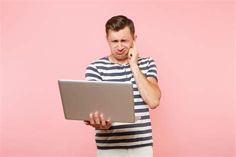 입고 슬픈 화가 젊은이의 초상화 노트북 컴퓨터 복사 공간 동향 파스텔 핑크 배경에 고립에서 작동 하는 T셔츠 줄무늬 사람들이 진심으 감정 라이프 스타일 개념 광고 영역입니다