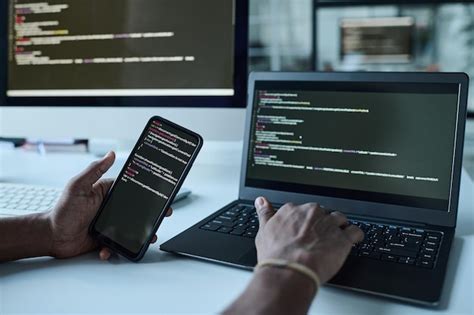 Premium Photo Developer Connecting Smartphone With Codes To Laptop