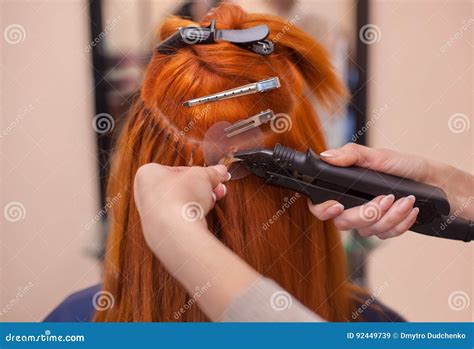 The Hairdresser Does Hair Extensions To A Young Red Haired Girl Stock