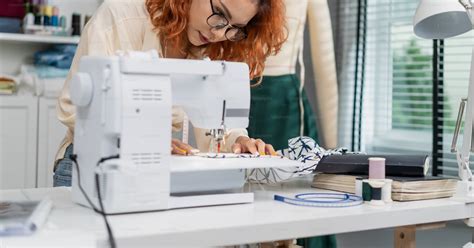 아시아의 아름다운 재단사 여자가 재봉 아틀리에에서 옷을 입고 있다 매력적인 젊은 여성 패션 디자이너는 작업장에서 새로운 수제 양복을 만드는 재봉틀을 통해 직물 재료를