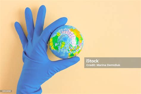 깨끗한 베이지 색 배경에 파란색 보호 장갑을 착용 한 지구 지구본 자연 생태 및 세계 평화를 보호하는 개념 손에 세계 지구