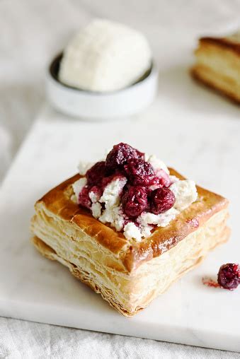 흰색 대리석 트레이에 리코타와 체리 소스를 곁들인 퍼프 페이스트리 스퀘어 치즈와 베리 소스를 얹은 구운 작은 사각형 케이크 0명에 대한 스톡 사진 및 기타 이미지 Istock