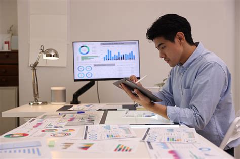 데스크톱 모니터에서 마케팅 보고서를 분석하고 종이 그래프 재무 통계 및 스타트업 프로젝트 인포그래픽을 검토하는 데 집중하는 사업가 그래프에 대한 스톡 사진 및 기타 이미지