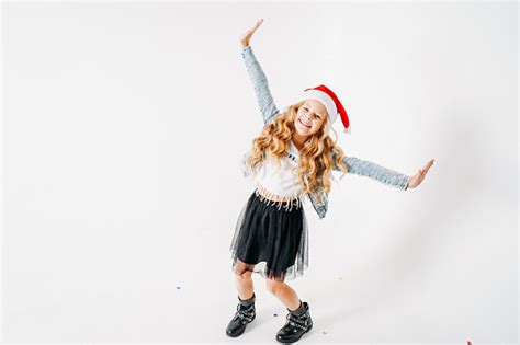 화려한 색종이와 흰색 배경에 산타 모자 데님 재킷과 검은 투투 스커트에 행복 유행 곱슬 머리 트웬트 소녀를 입고 12월에 대한