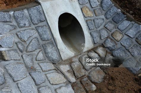 새로 지어진 도로로 그 층에는 스크 리드와 아스팔트 카펫이 연속적으로 보입니다 주변 지역은 콘크리트 홈통이있는 도랑으로 경사져 있습니다 빗물 배수 0명에 대한 스톡 사진 및