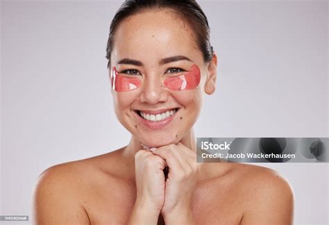 스킨케어 초상화 그리고 스튜디오 배경에 노화 방지 얼굴을 위해 얼굴에 아이 패드를 가진 아시아 여성 뷰티 화장품 콜라겐 마스크 또는 패치를 착용한 여성으로 신선한 피부 미소