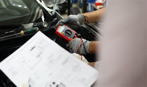 멀티 미터를 사용하여 자동차 배터리 및 자동차 문서 다이어그램의 전압 레벨을 확인하는 기계 서비스 고압 전류 주의에 대한 스톡 사진 및 기타 이미지 Istock