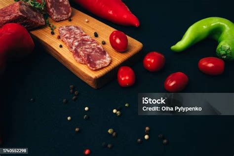 녹색 종이와 토마토가 든 나무 쟁반에 다양한 종류와 크기의 소시지 어두운 나무 배경에 훈제 소시지 세트 가공육에 대한 스톡 사진