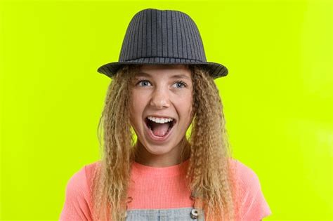 모자와 함께 카메라를 보고 곱슬 머리 놀된 행복 한 십 대 소녀 노란색 스튜디오 배경 위에 입을 열으십시오 곱슬 머리에 대한 스톡 사진 및 기타 이미지 Istock