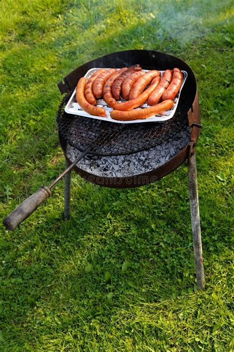 Fresh Sausages On A Grill Outdoor Barbecue On The Grass Background