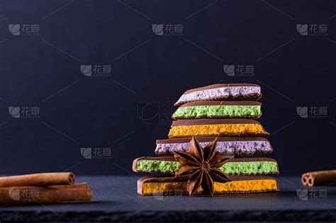 黑色背景的巧克力和水果馅巧克力片配蓝莓薄荷和橘子黑巧克力肉桂棒和大茴香板