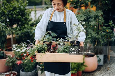 자신감 아시아 여성 꽃집의 초상화 중소 기업 꽃 가게의 소유자 꽃가게 밖에서 꽃과 식물로 가득찬 나무 상자를 들고 있다 미소와 식물을 보고 꽃과 함께 하는 그녀의 일을