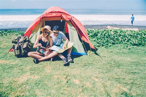 함께 열대 섬을 탐험 하는 여행을 계획 하는 가이드와 지도 사용 하 여 바다 근처 녹색 해안선에 캠핑 힙스터 커플남성과 여성