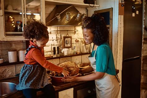 아프리카 계 미국인 딸이 추수 감사절 저녁 식사를 위해 로스트 칠면조를 꾸미는 어머니를 도왔습니다 딸에 대한 스톡 사진 및 기타 이미지 Istock