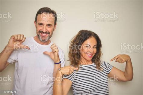 아름다운 중년 부부는 함께 고립 된 흰색 배경 위에 서서 얼굴에 미소를 지으며 자랑스럽고 행복한 손가락으로 자신을 가리킵니다 2명에 대한 스톡 사진 및 기타 이미지 Istock