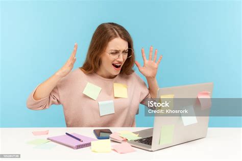 우울하고 스트레스를 받고 과로한 여성 직원이 끈적끈적한 메모로 덮인 안경을 쓰고 화를 내며 손을 들고 비서에 대한 스톡 사진 및