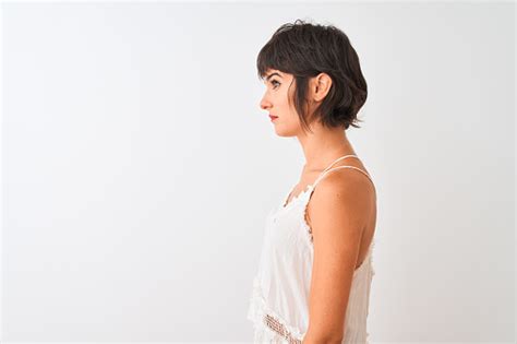 여름 캐주얼 티셔츠를 입은 젊은 아름다운 여성은 옆으로 찾고 고립 된 흰색 배경 위에 서서 자신감있는 미소로 자연스러운 얼굴로 프로필 포즈를 취합니다 인물 사진에 대한 스톡