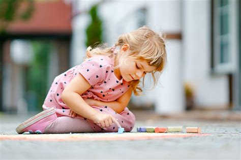 작은 유치원 소녀는 뒤뜰에 땅에 화려한 분필 무지개 그림 긍정적 인 행복한 유아 아이 그림과 그림을 만듭니다 여름에는 창의적인 야외 활동 공예에 대한 스톡 사진 및 기타