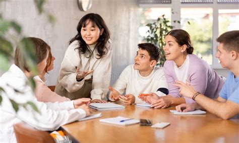 Young Teacher Discussing Her Notes With Students Around The Table Stock Young Teacher Discussing Her Notes With Students Around The Table Stock