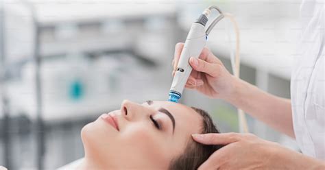 얼굴 피부 관리 젊은 여성의 클로즈업은 미용실에서 얼굴 하이드로 진공 미세 박피술 필링 치료를 받고 있습니다 악기에 집중 사진 Unsplash의 진단 이미지